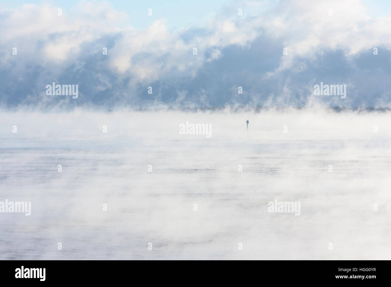 Small marine buoy or sea mark in a very misty vaporing sea at winter ...