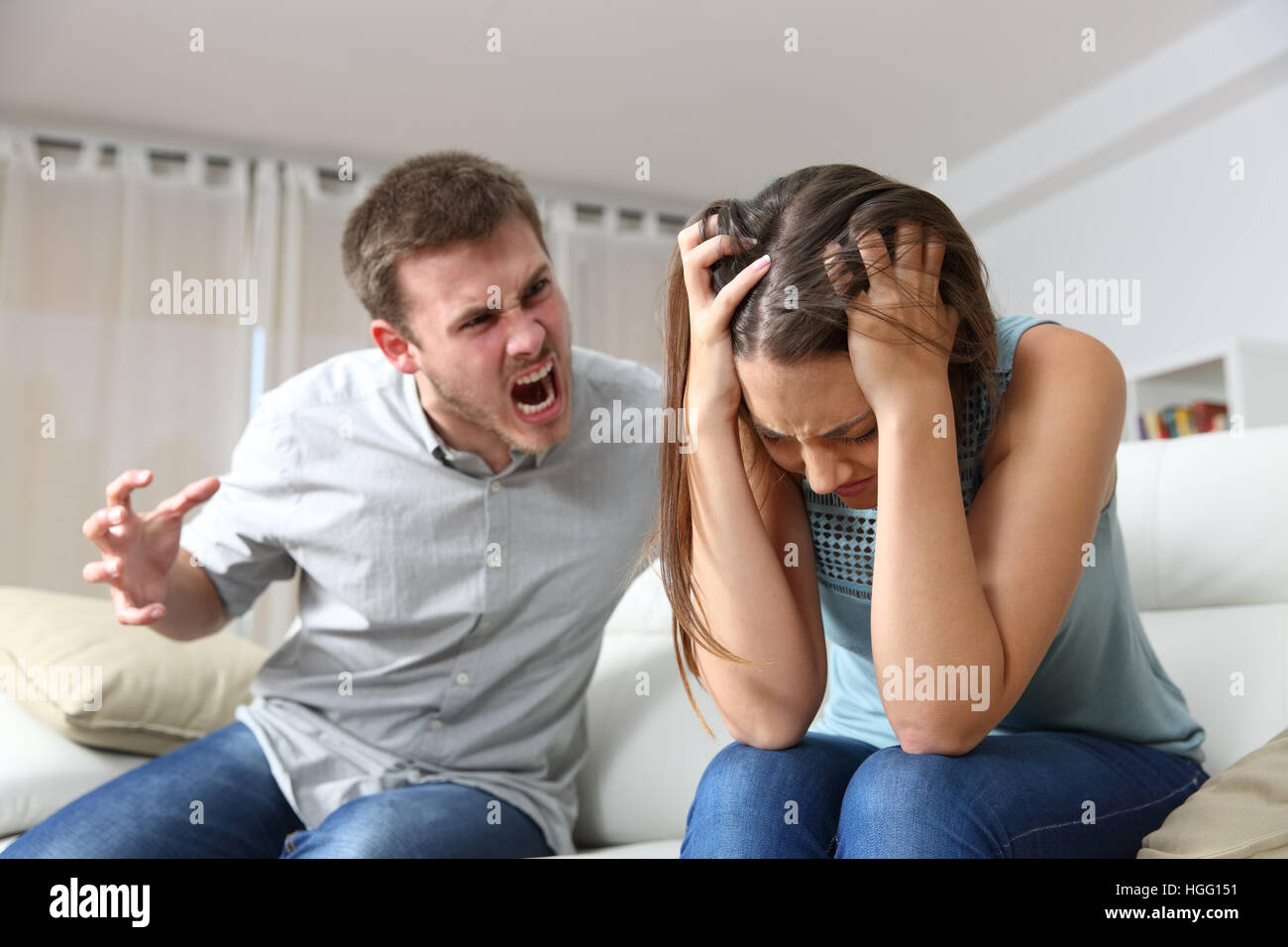 Couple arguing. Husband shouting to a scared wife in a house interior ...