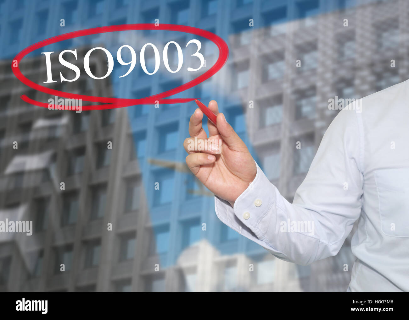 Hand of young businessman write the word ISO 9003 on skyscrapers ...