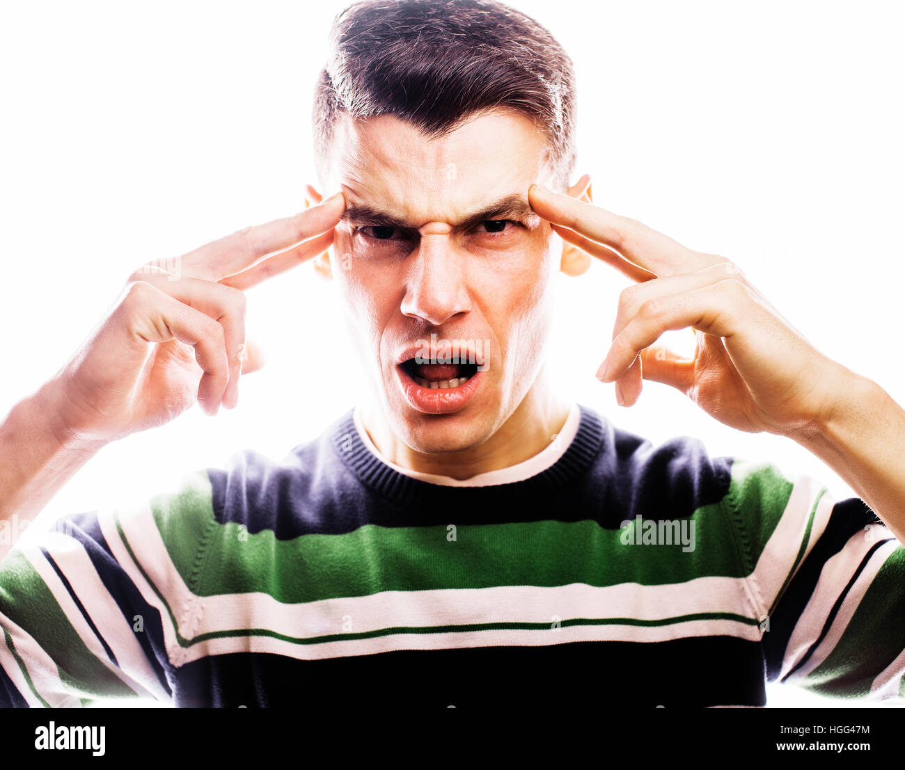 Portrait of a smart serious young man standing against white background ...