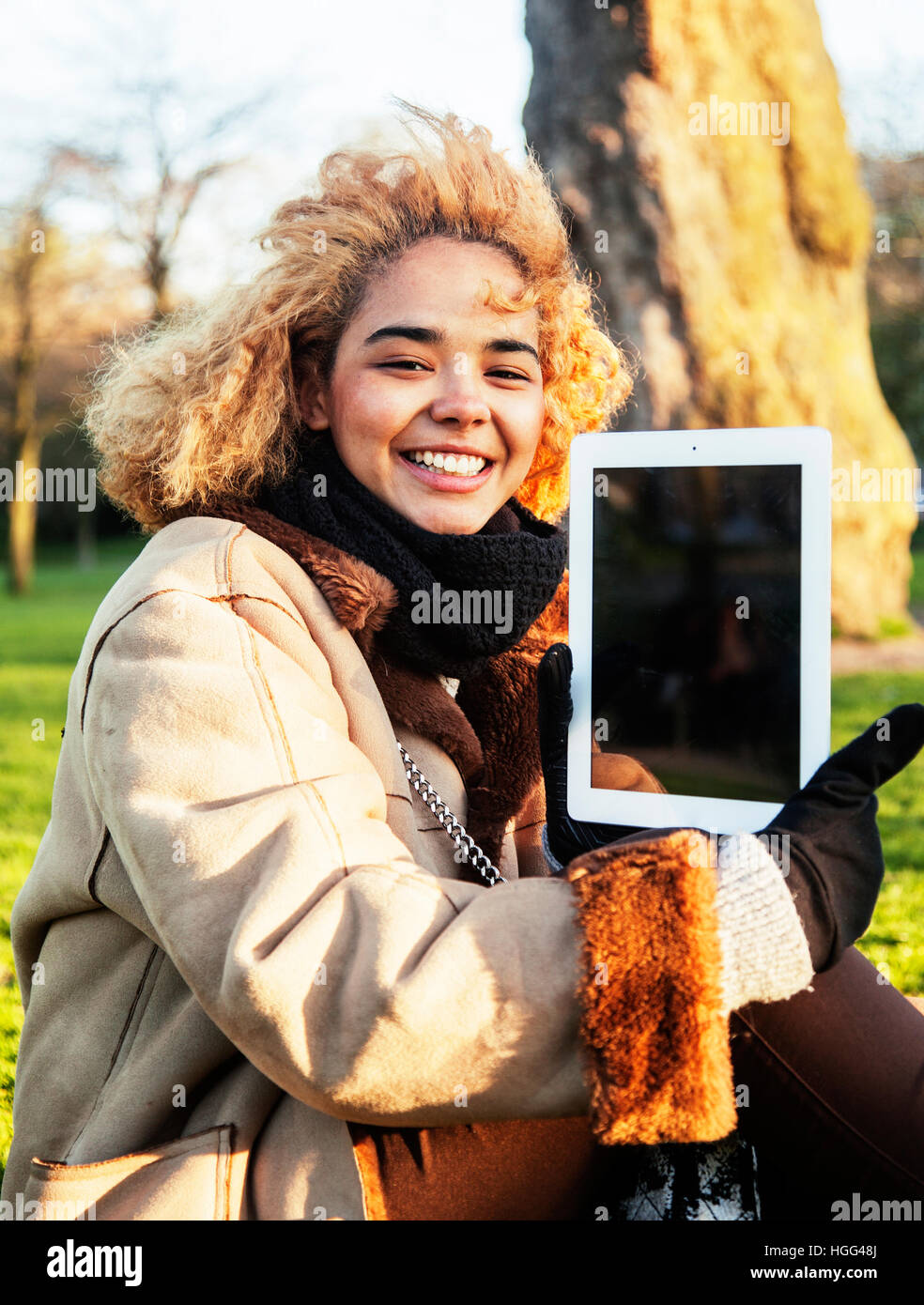 young cute blond african american girl student holding tablet and ...