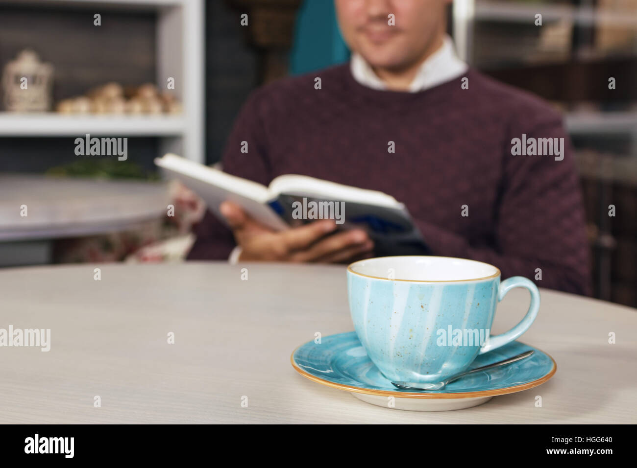 Young man sitting in cafe and reading a book Stock Photo - Alamy