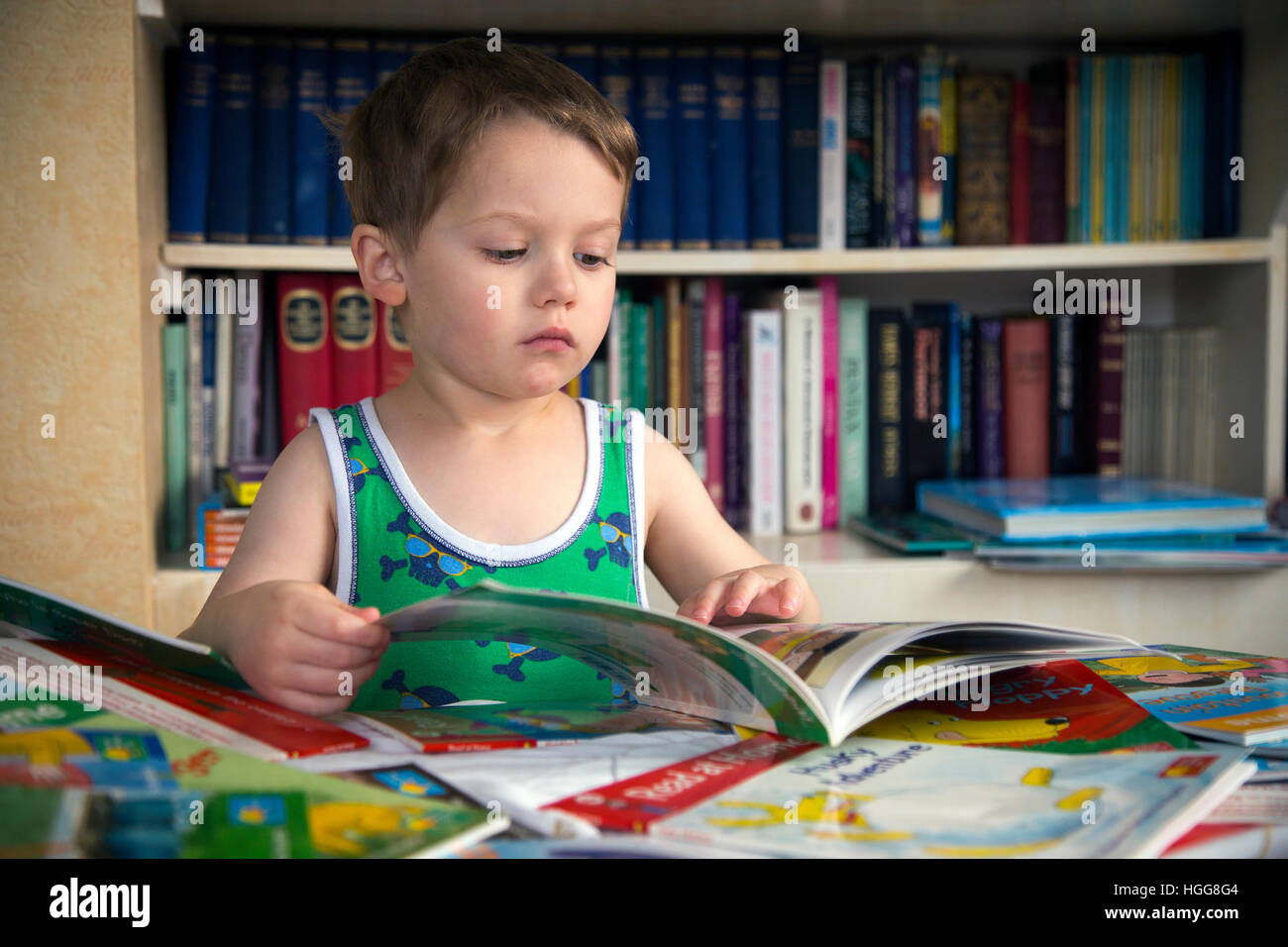 preschool child looks at books with library in background, reading ...