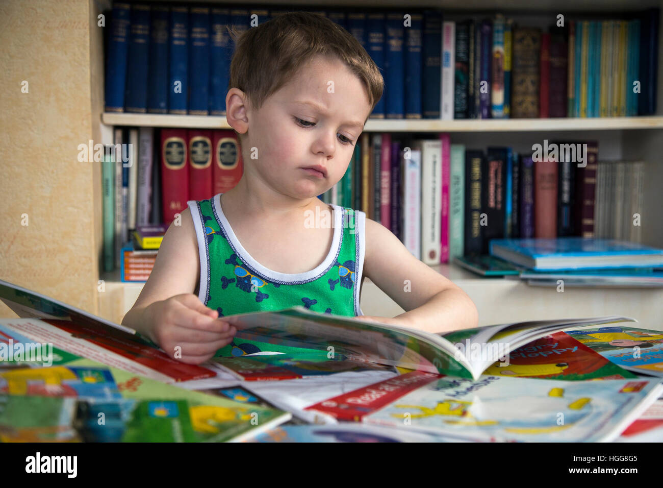 preschool child looks at books with library in background, reading ...