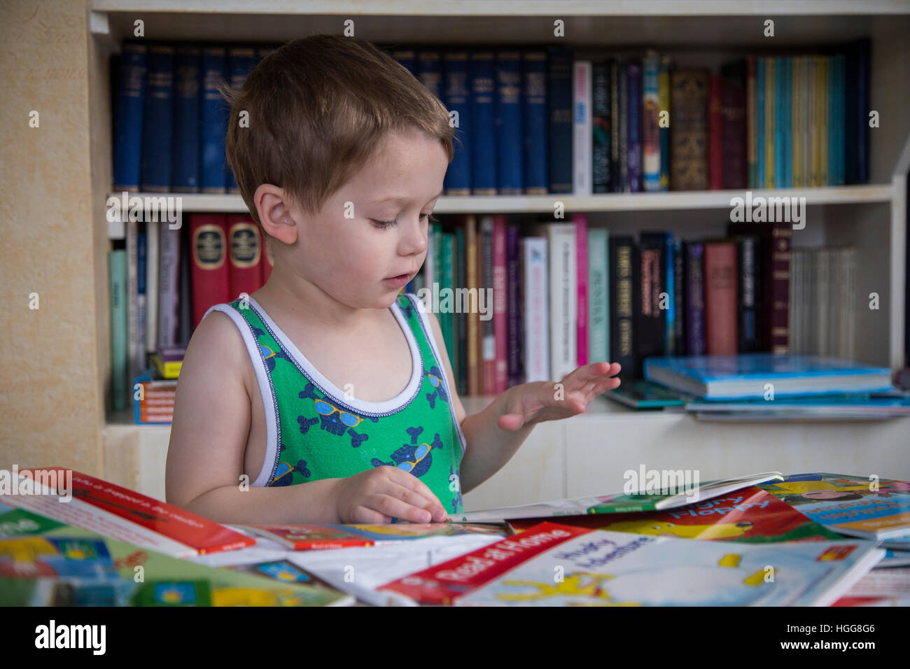 preschool child looks at books with library in background, reading ...