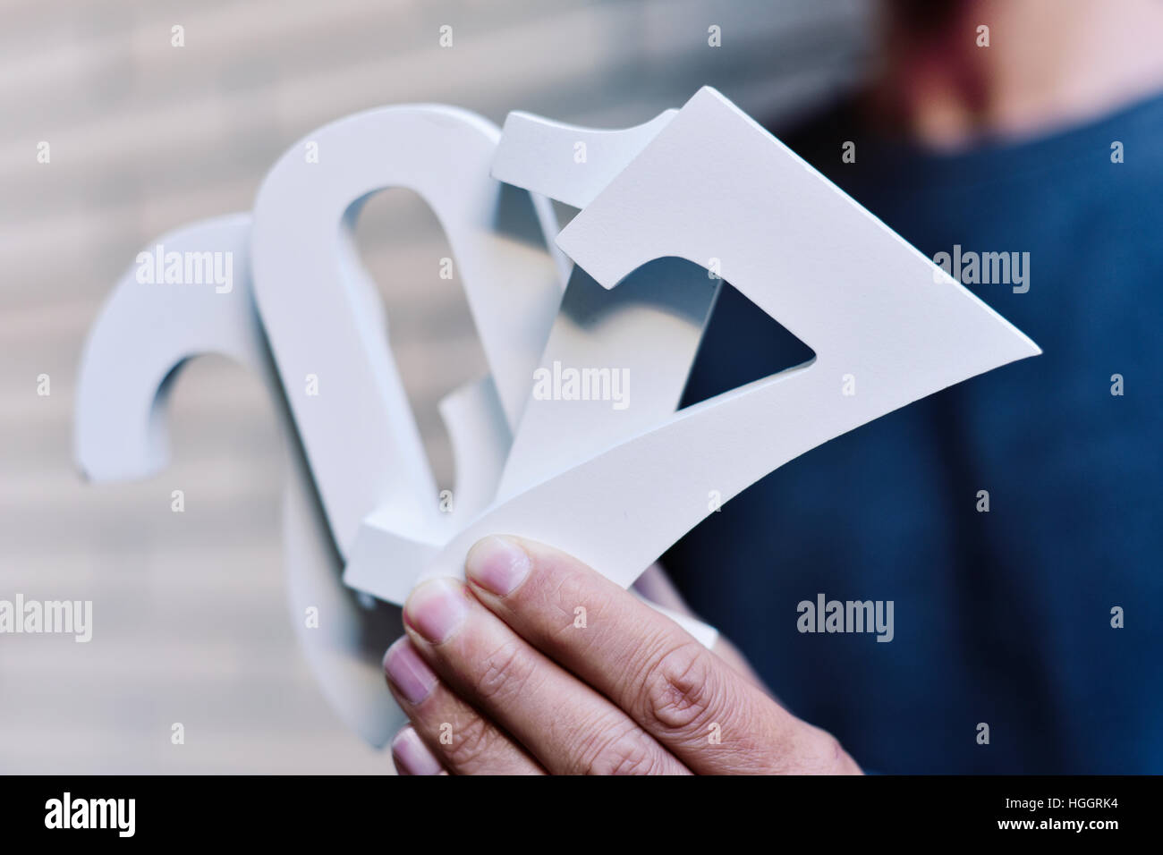 closeup of a young man holding some white numbers forming the number ...