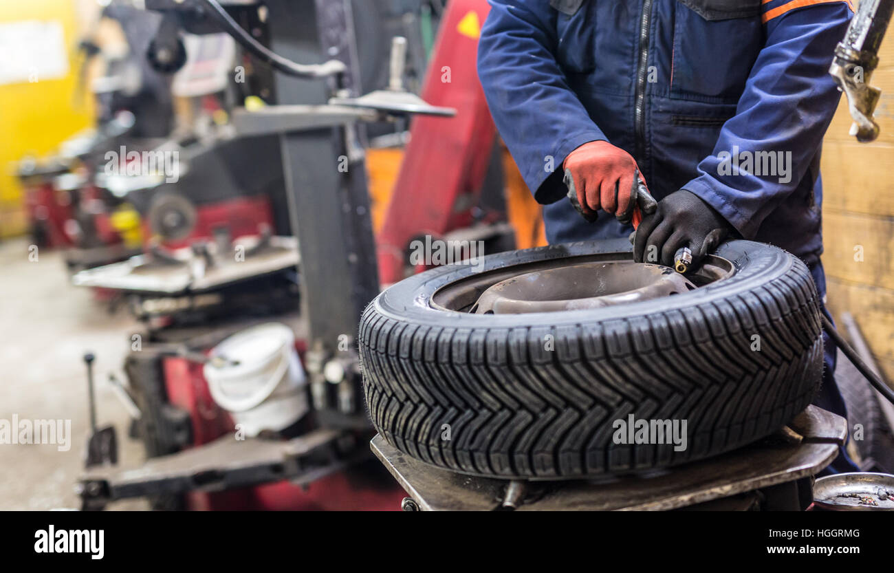 Professional auto mechanic replacing tire on wheel in car repair ...
