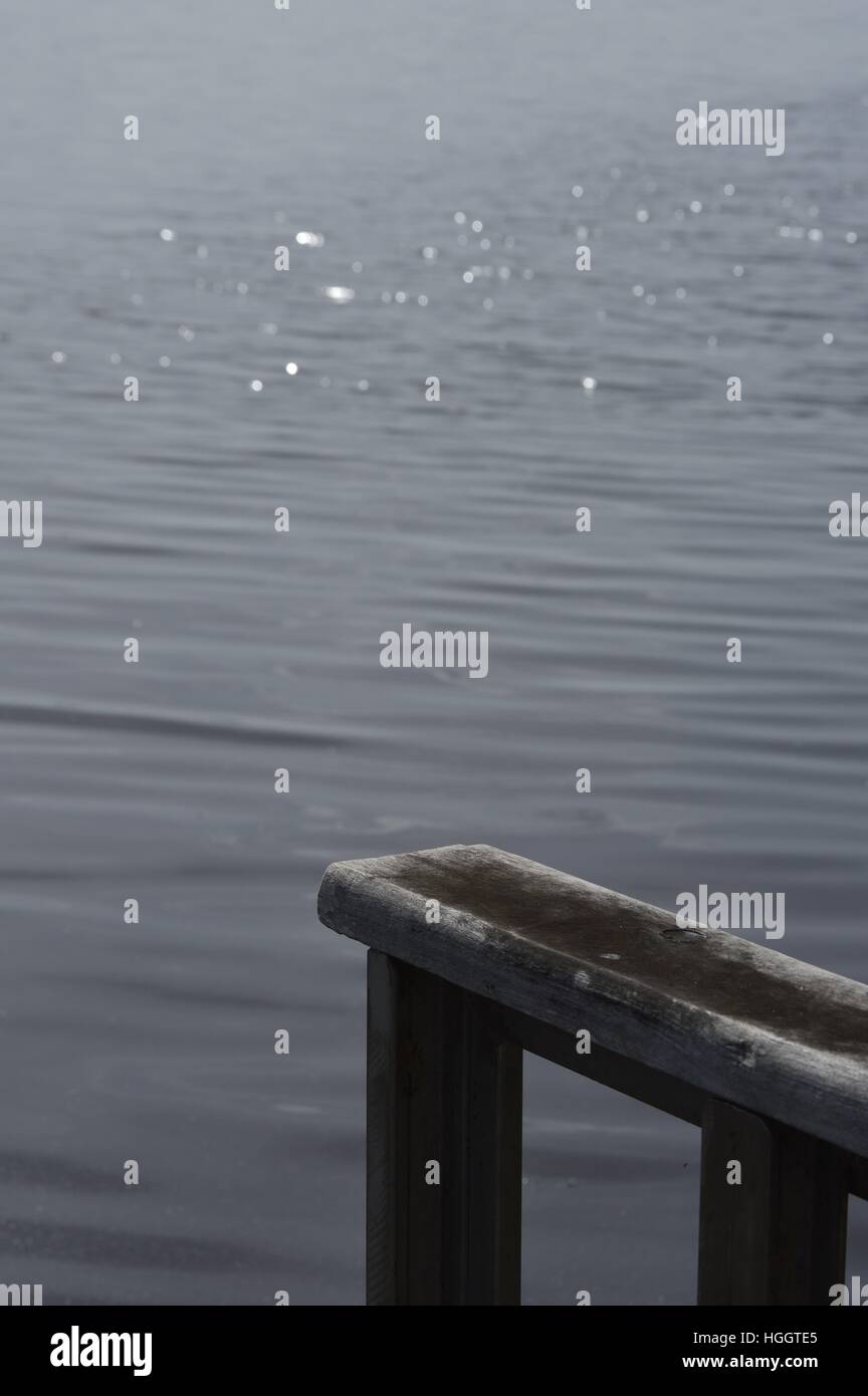 Wooden railing with bright water ripples in the background Stock Photo ...