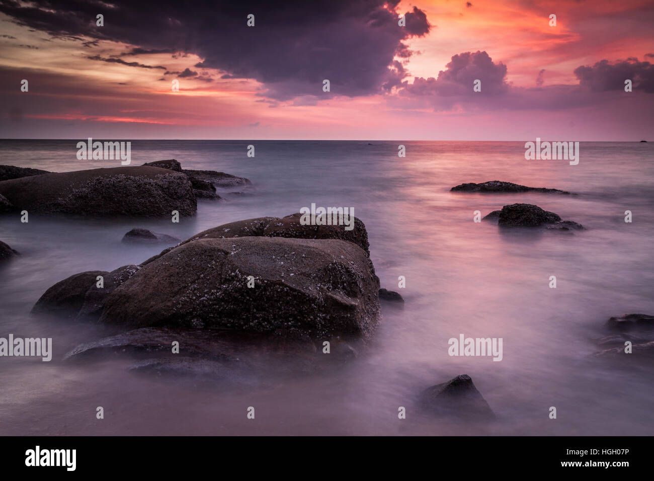 Sunset at the beach with stones Stock Photo - Alamy