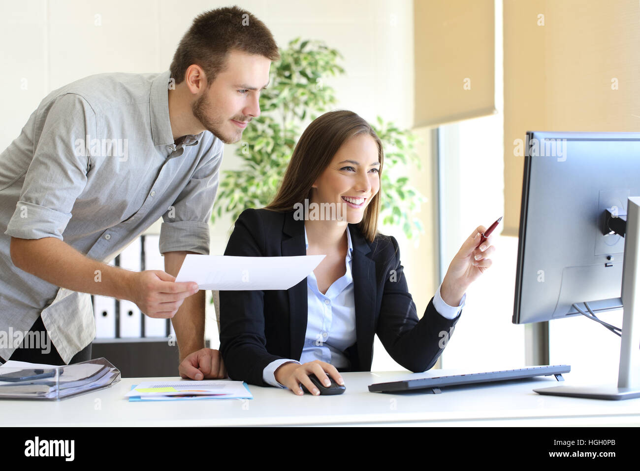 Businesspeople co-working comparing a desktop computer information with ...