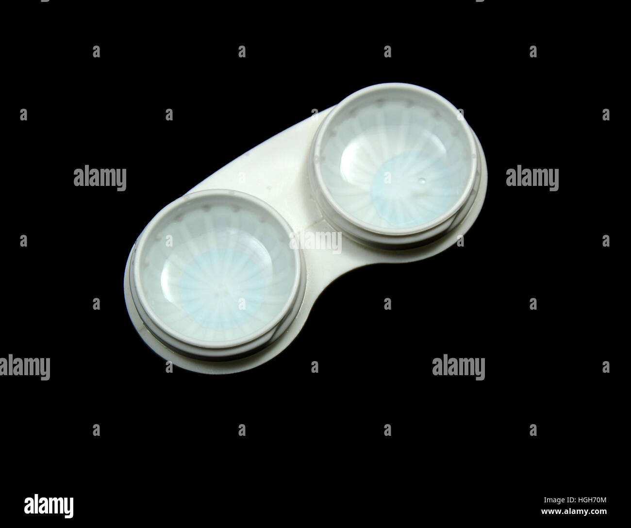 Contact lens case filled with solution and contacts on a black ...