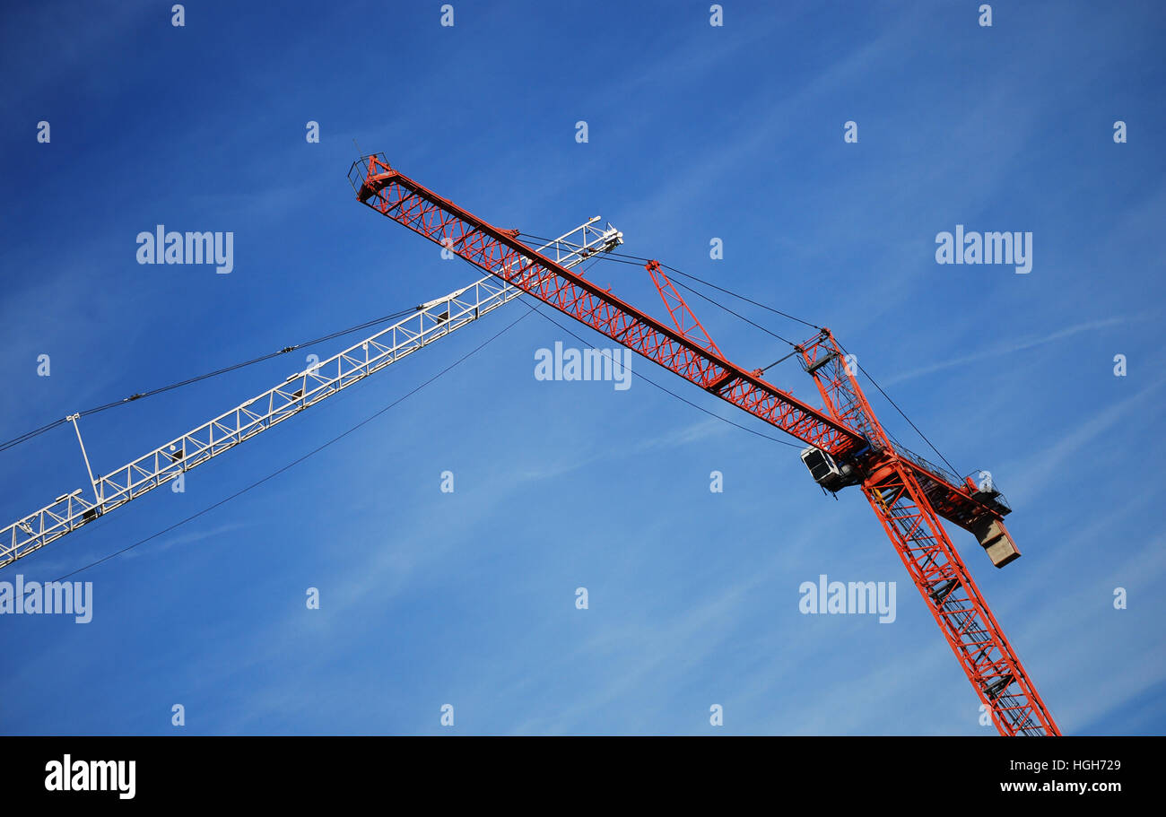 Two tower cranes building at a construction site against blue sky Stock ...
