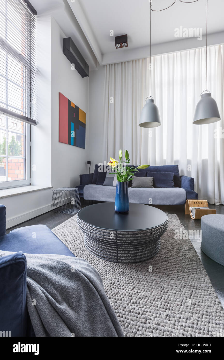 Living room with round, small table and blue sofa Stock Photo - Alamy