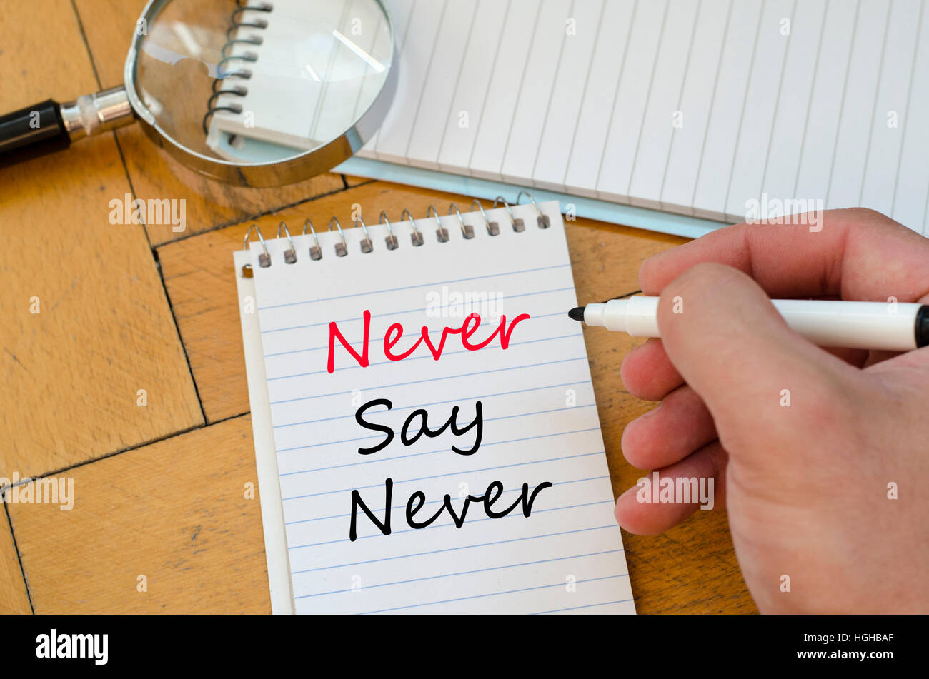 Human hand over wooden background and never say never text concept ...