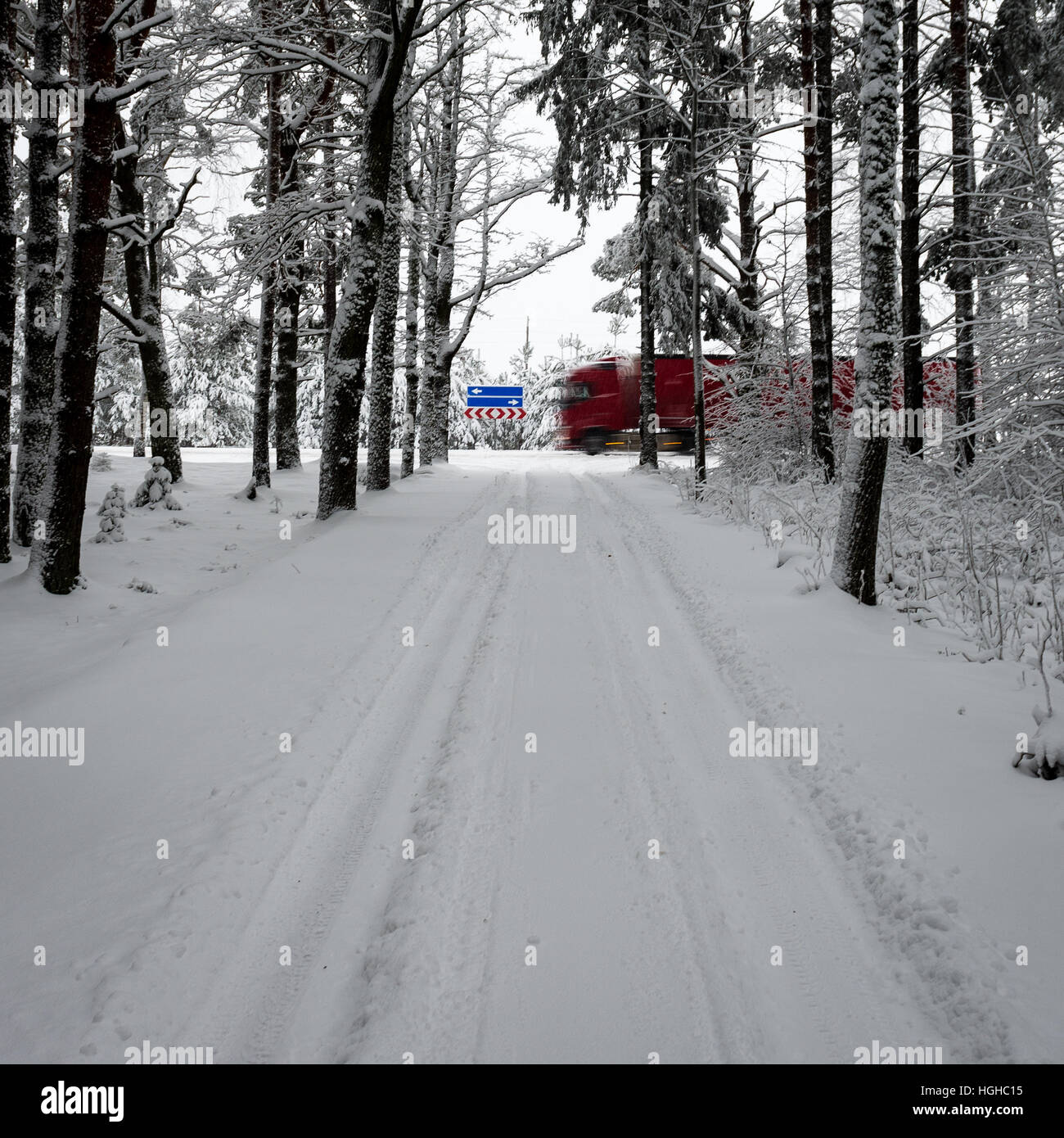 car tire tracks on winter road in deep snow in lonely forest with road ...