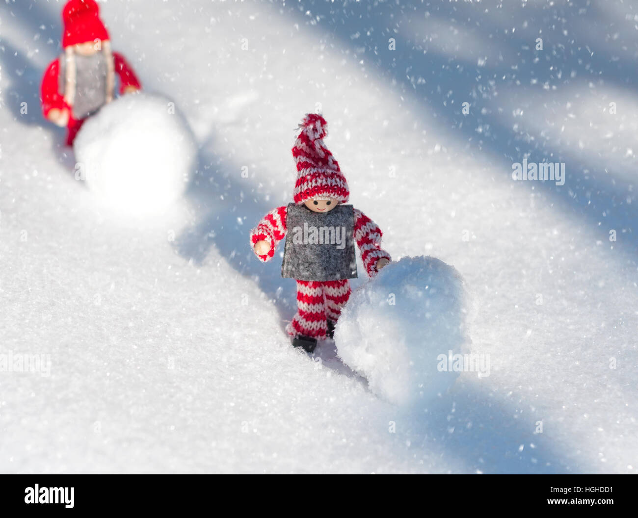 Two toy little men playing in the snow, snowfall, pushing snow balls ...