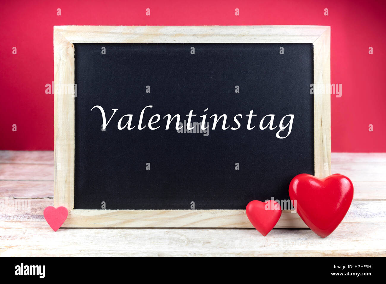 Wooden blackboard with red hearts and written word in German ...