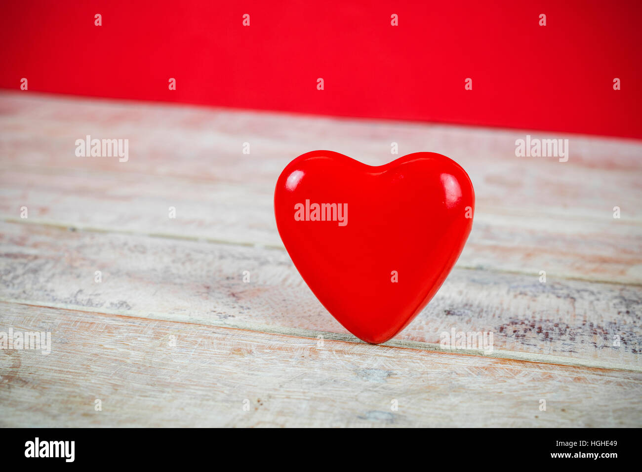 Closeup of red heart figure on wooden table in red background Stock ...