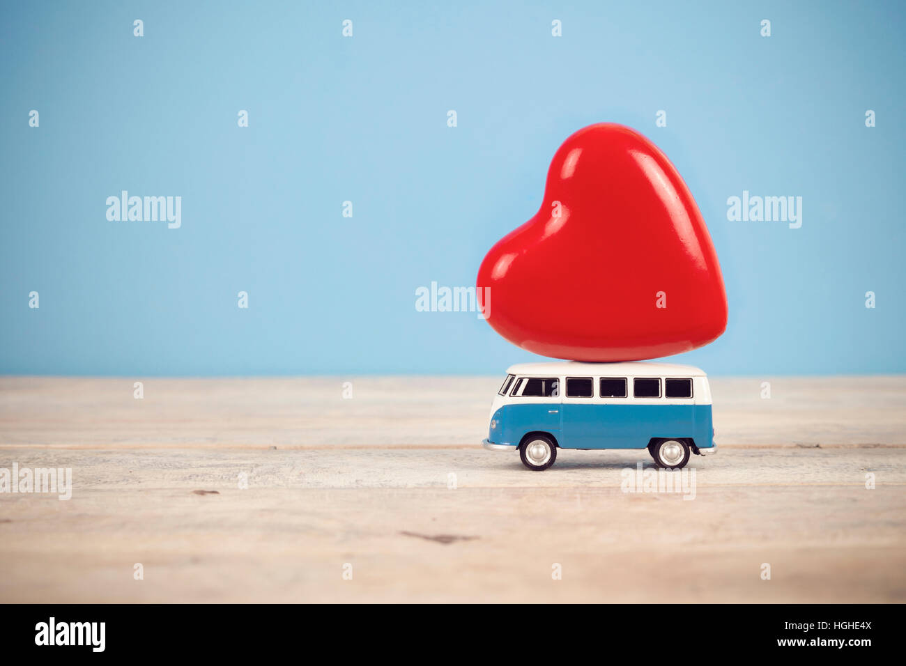 Old vintage toy van with big red heart figure on top in blue background ...