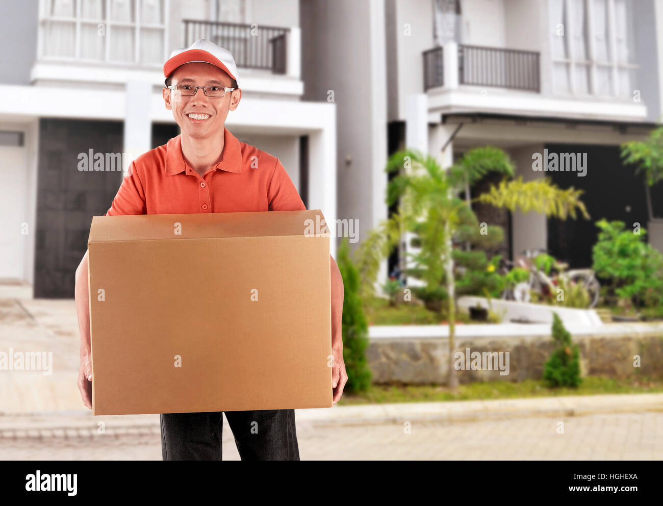 Smiling asian courier delivering the package in the city Stock Photo ...