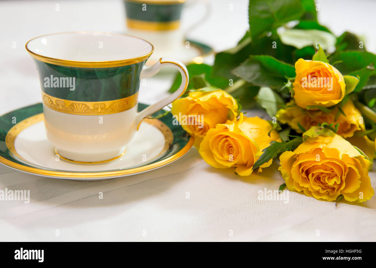 Yellow roses next to a green tea cup Stock Photo - Alamy