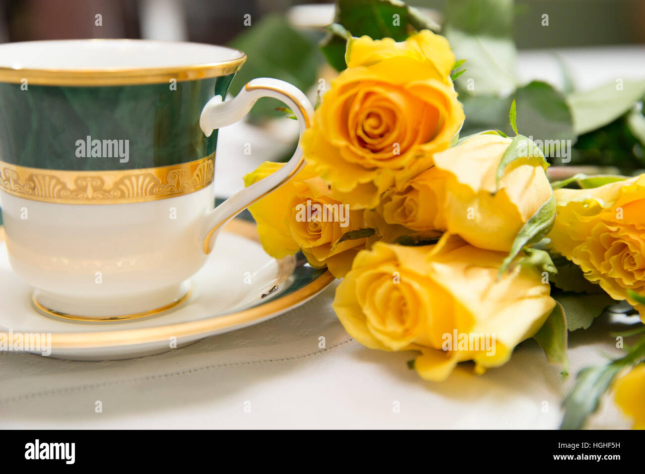 Dinner table with yellow roses and a green tea cup Stock Photo - Alamy