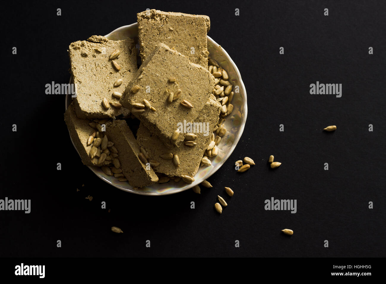 Sunflower halva with seeds on plate, on black background Stock Photo - Alamy