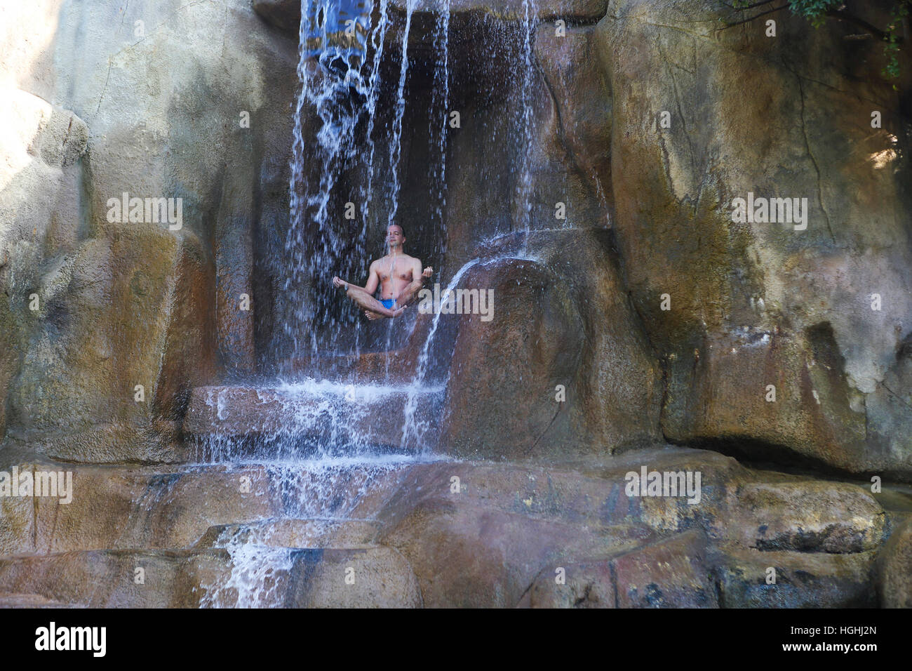 Man meditating under waterfall. Yoga practicing outdoors Stock Photo ...