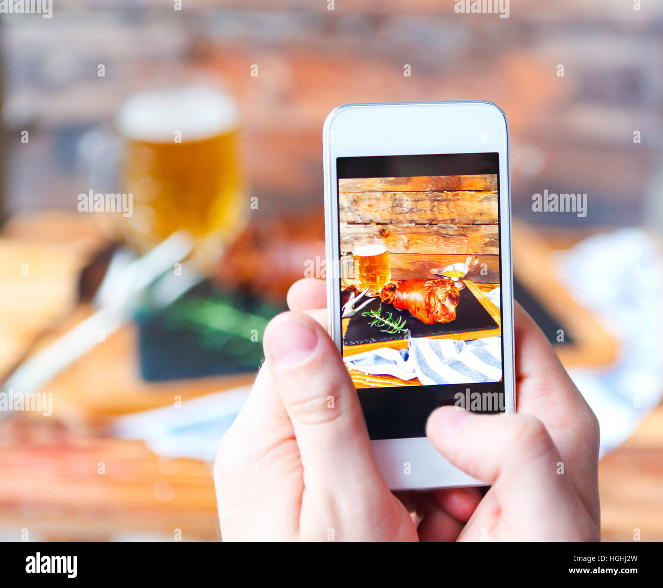 Wiman making photo on phone of roasted pork leg (rulka) served with ...