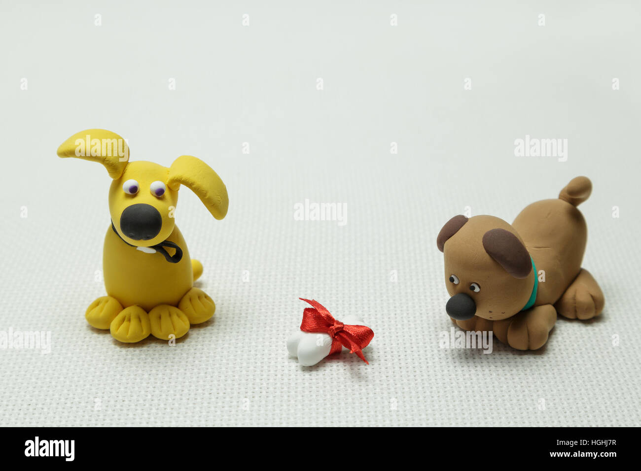 Toys of two dogs from plasticine and a bone tied up by a band on a ...
