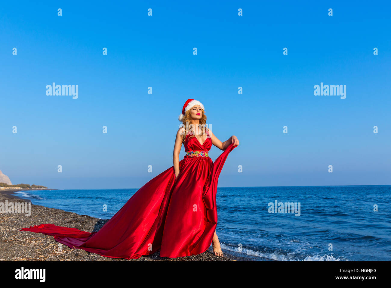 Beautiful woman in red dress goes in the sea Stock Photo - Alamy