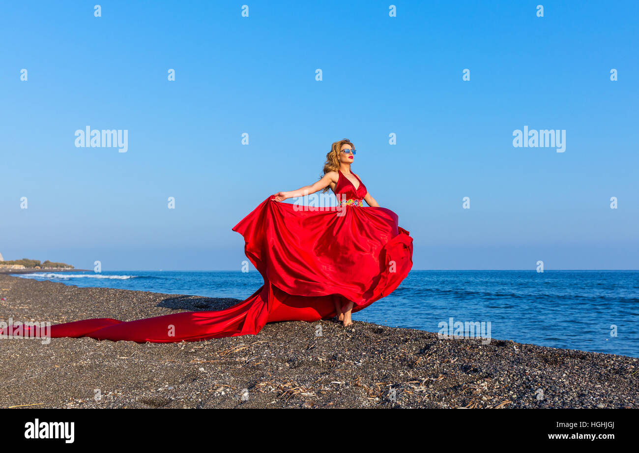 Beautiful woman in red dress goes in the sea Stock Photo - Alamy