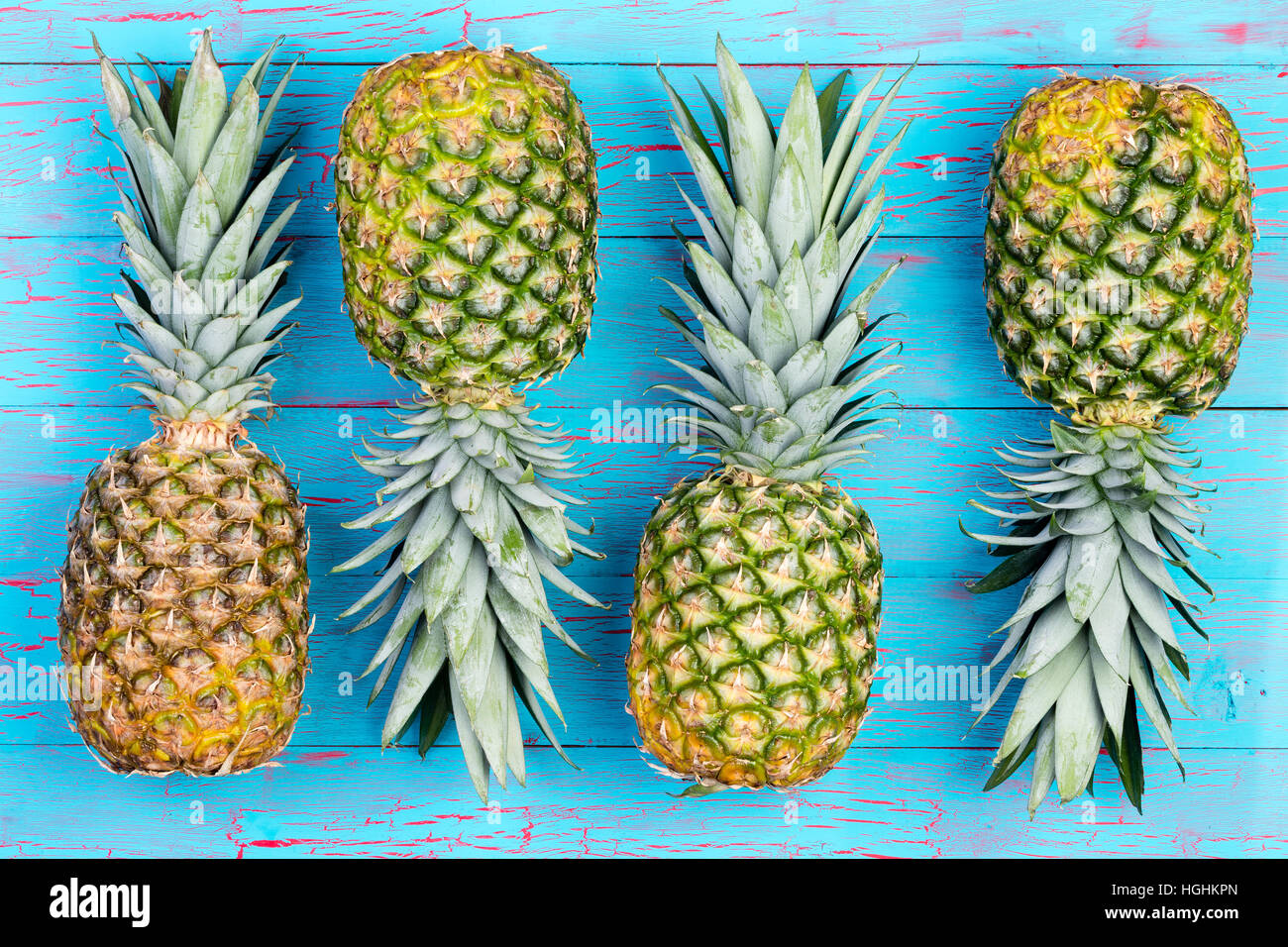 Four pineapple fruits arranged alternating next to each other on old ...