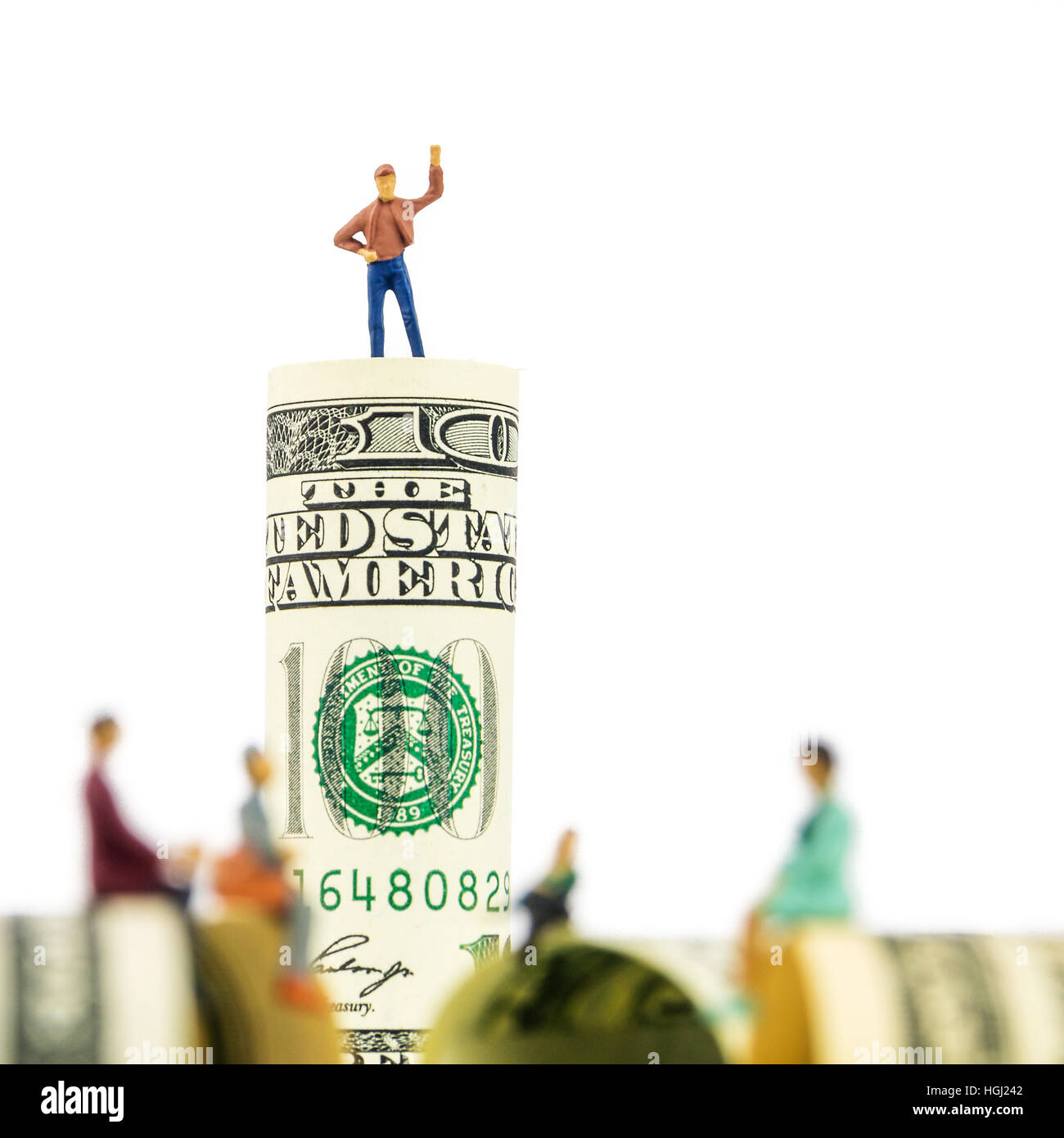 defocused miniature figurines sitting on the edge of 100 dollar ...