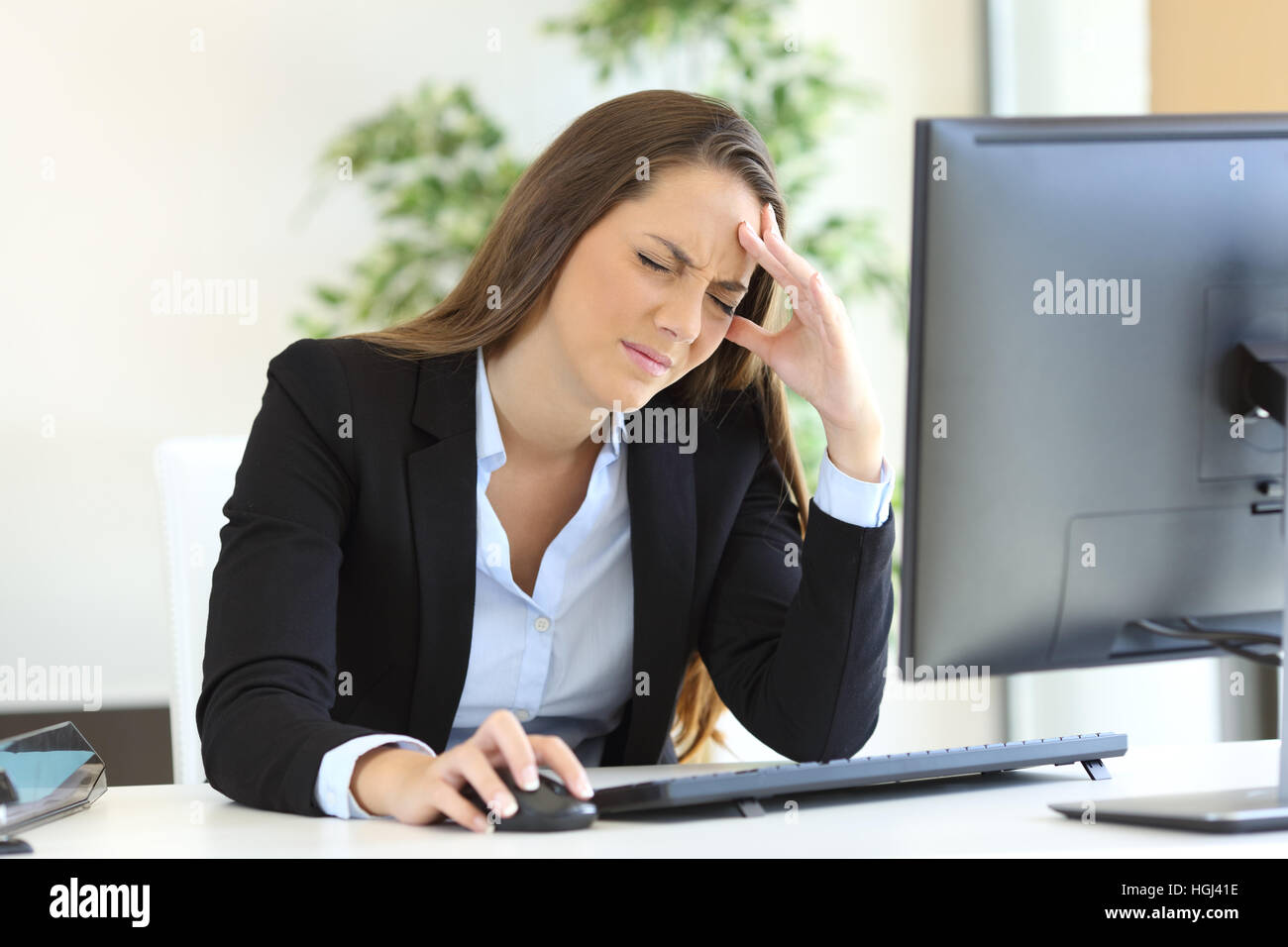 Businesswoman suffering headache at work using a desktop computer in ...