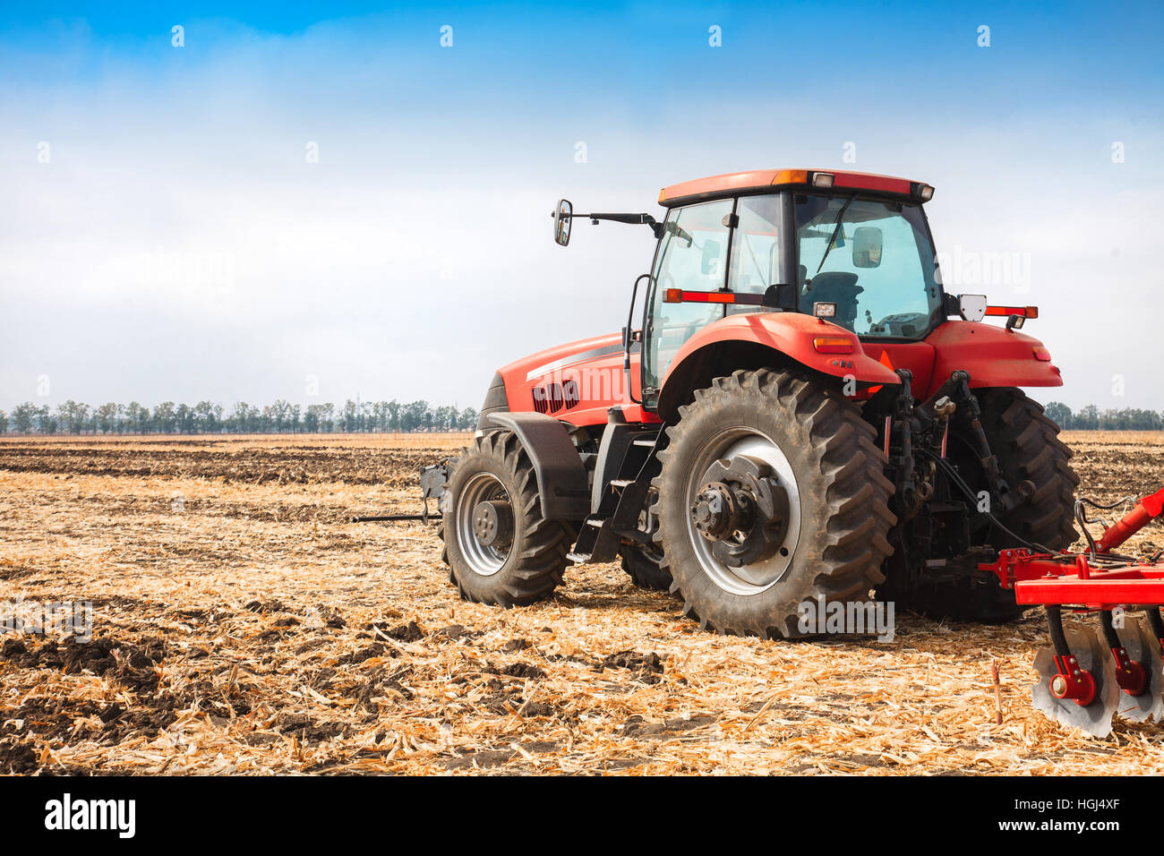 Red tractor working in a field on a bright sunny day Stock Photo - Alamy