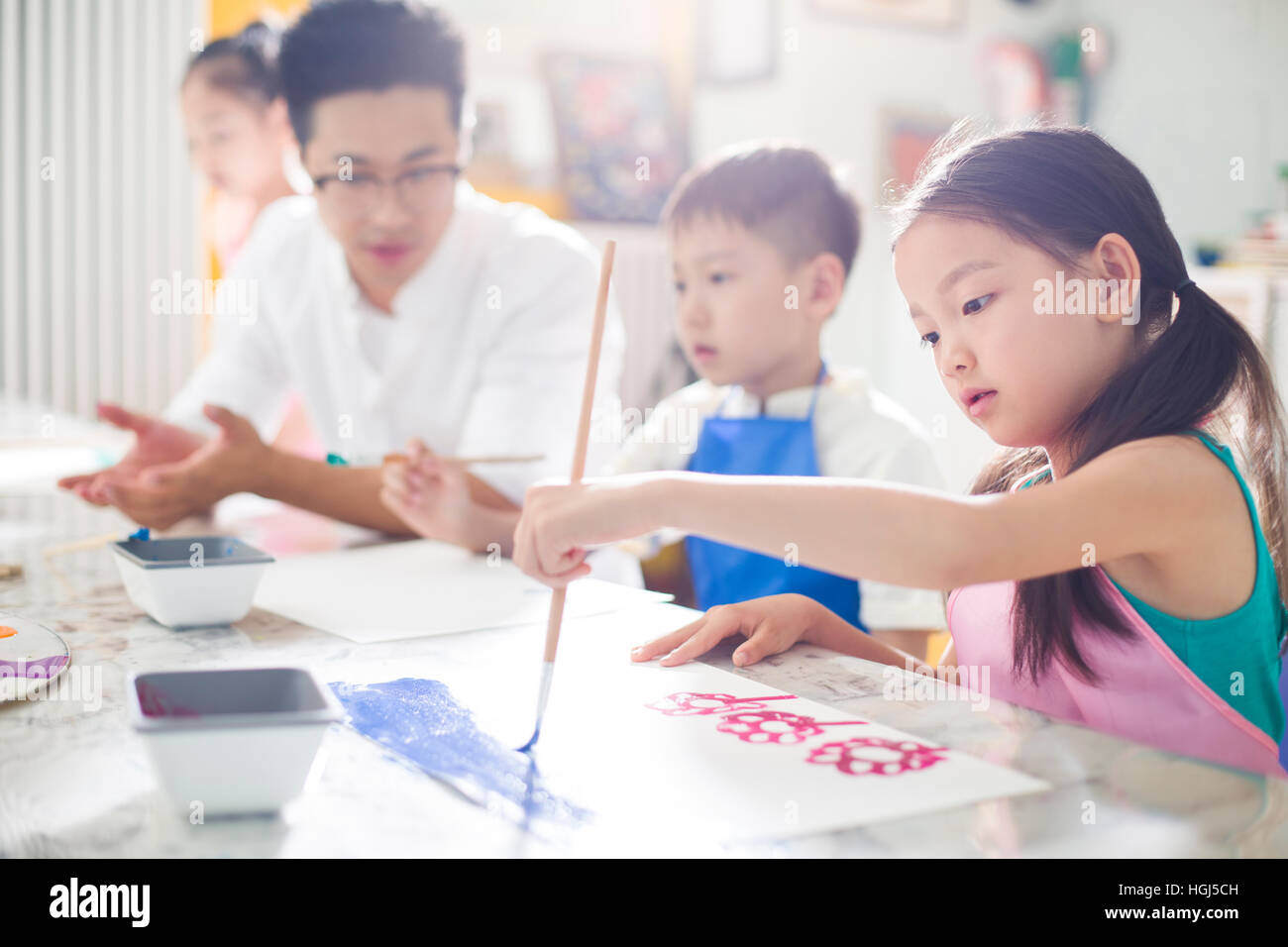 Little children painting in art class with teacher Stock Photo - Alamy
