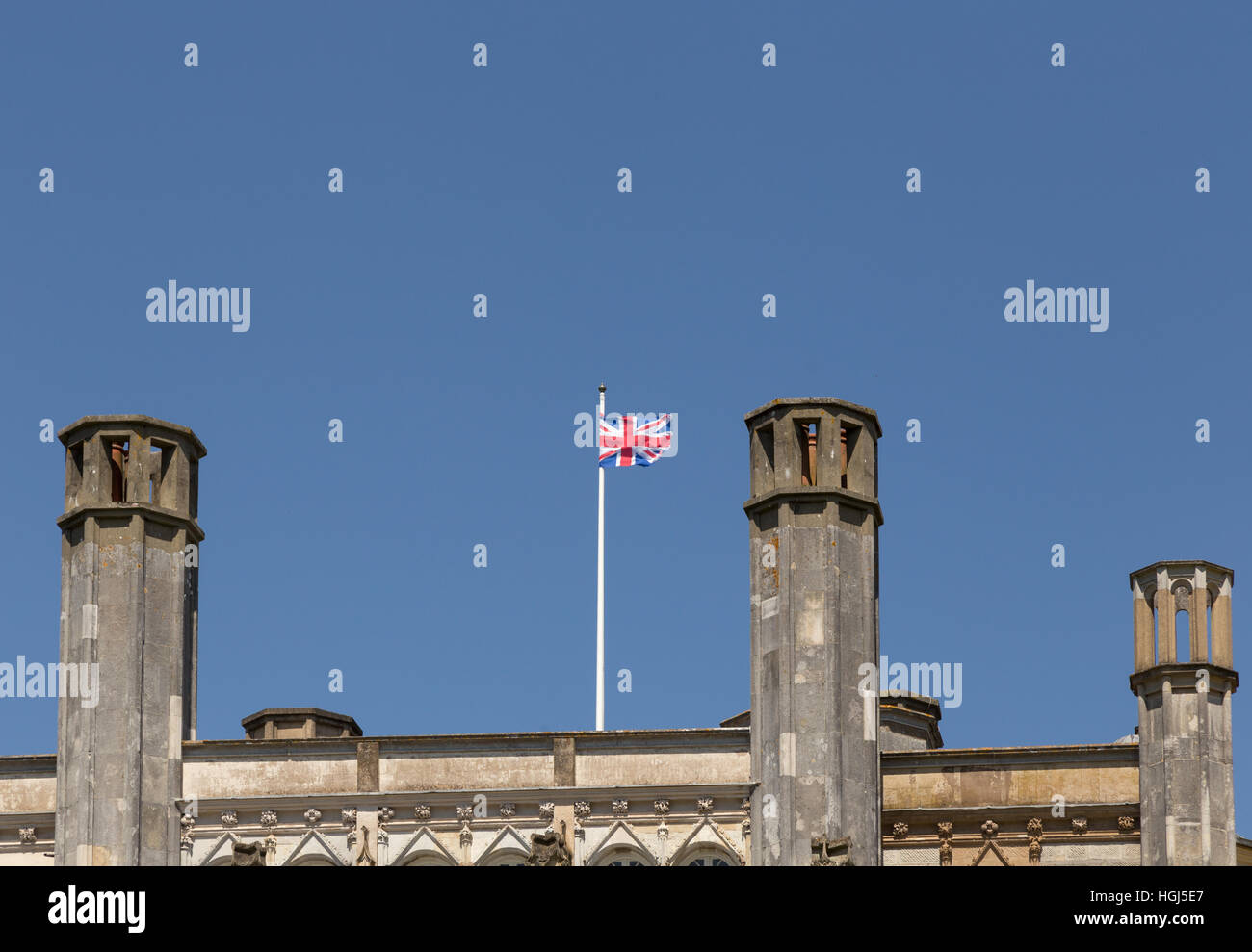 Union Jack flag flying on a castle roof top, with chimneys and a blue ...