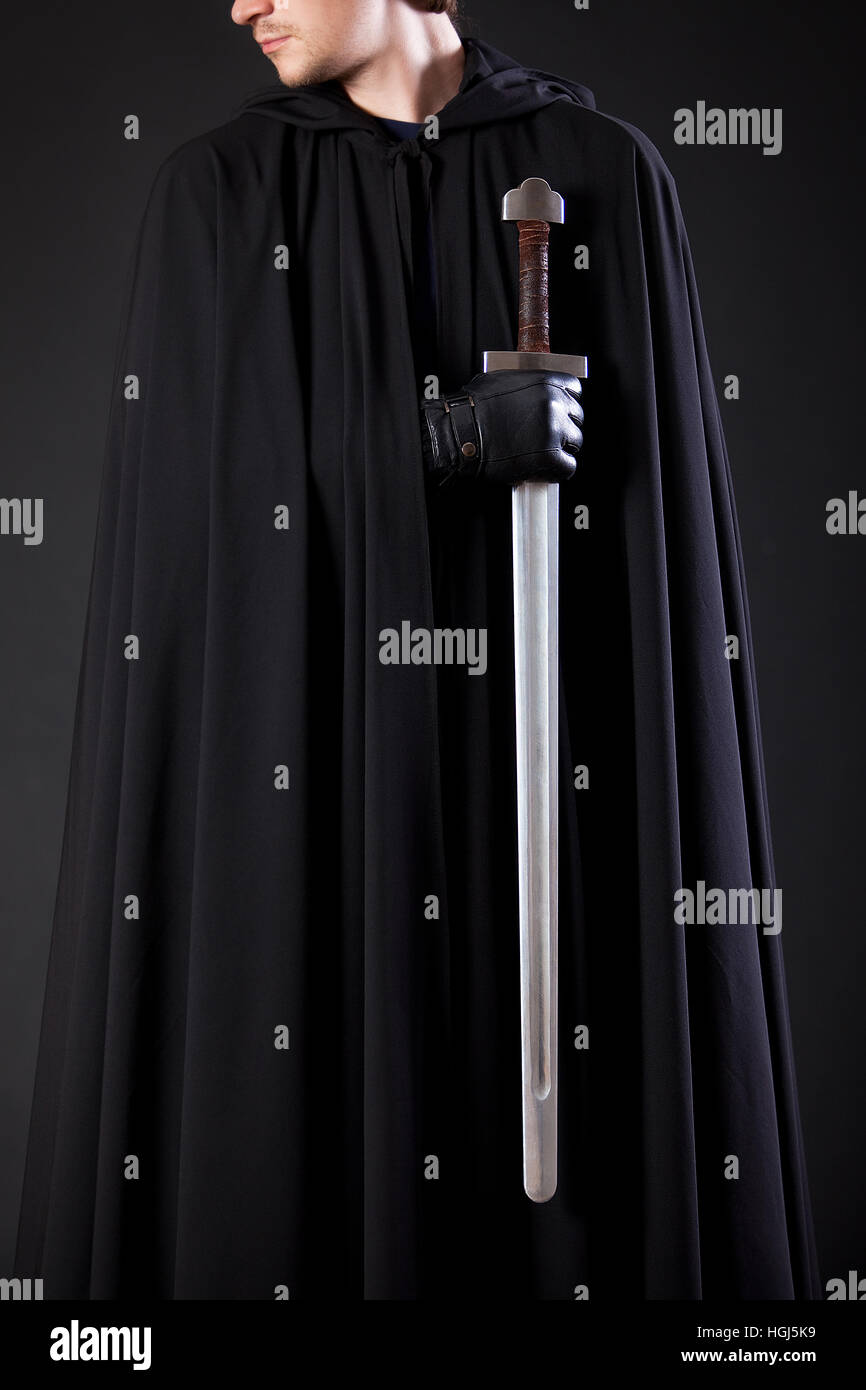 Portrait of a courageous warrior wanderer in a black cloak and sword in ...