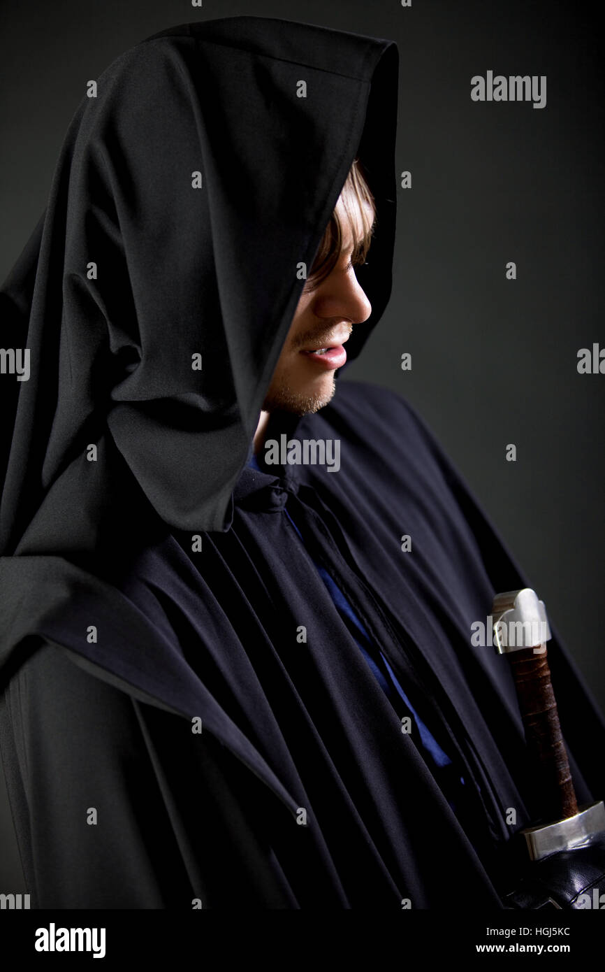 Portrait of a courageous warrior wanderer in a black cloak and sword in ...