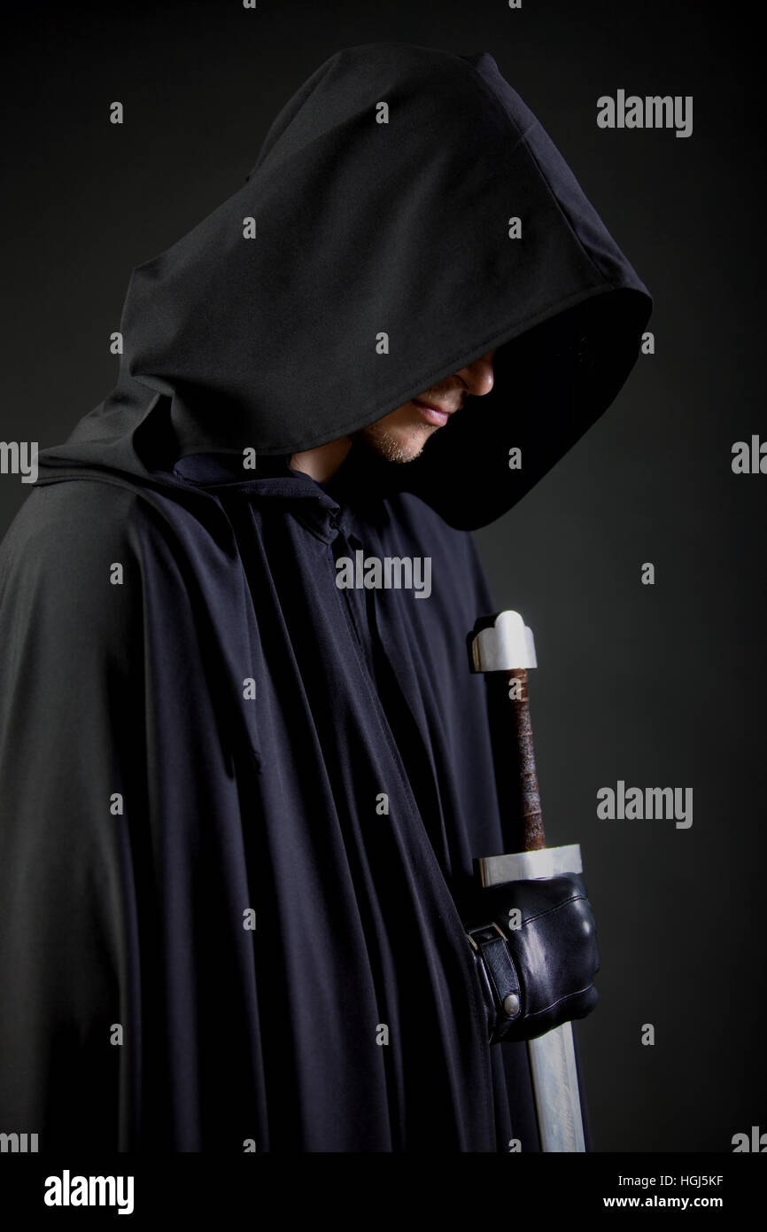 Portrait of a courageous warrior wanderer in a black cloak and sword in ...