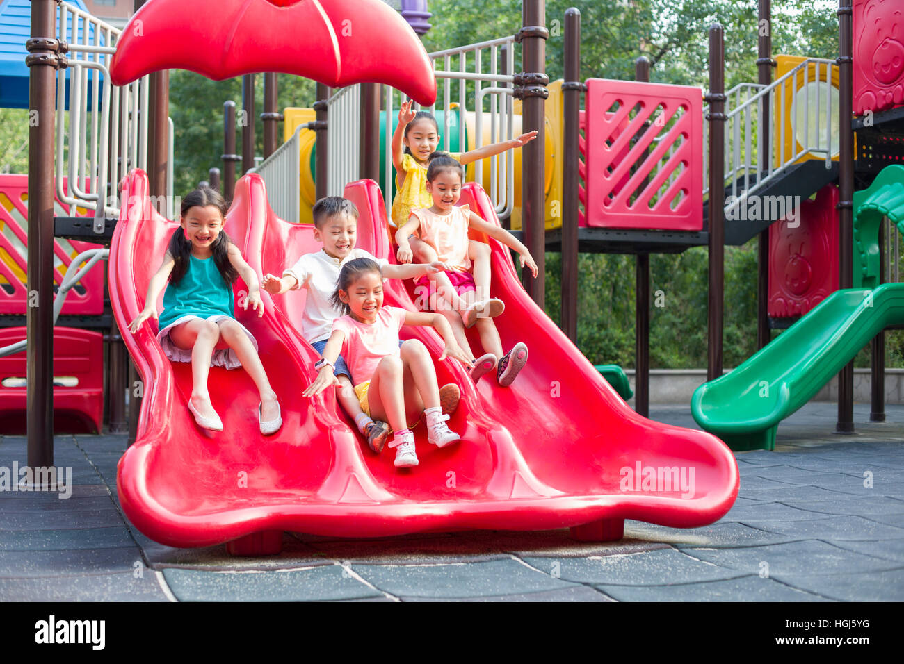 Happy children playing on slide Stock Photo - Alamy