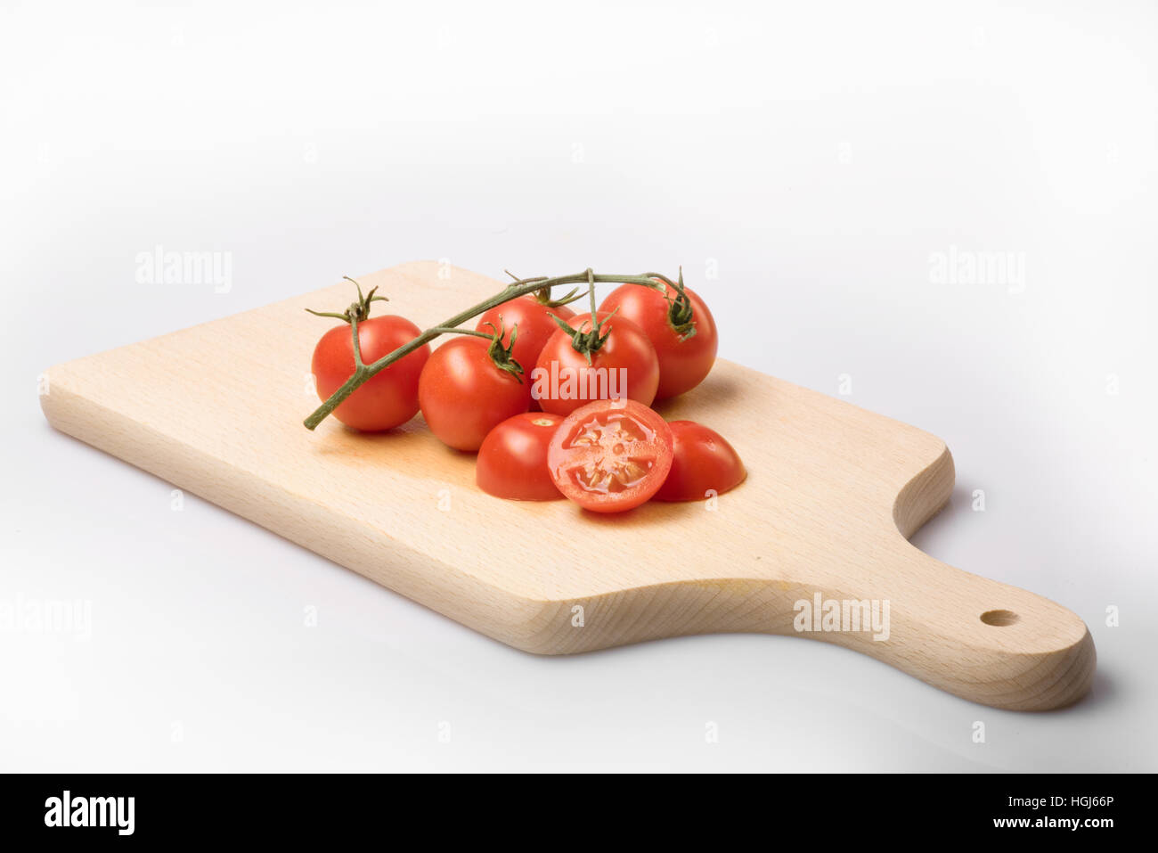 Tomato sliced on wooden cut board on white background Stock Photo - Alamy
