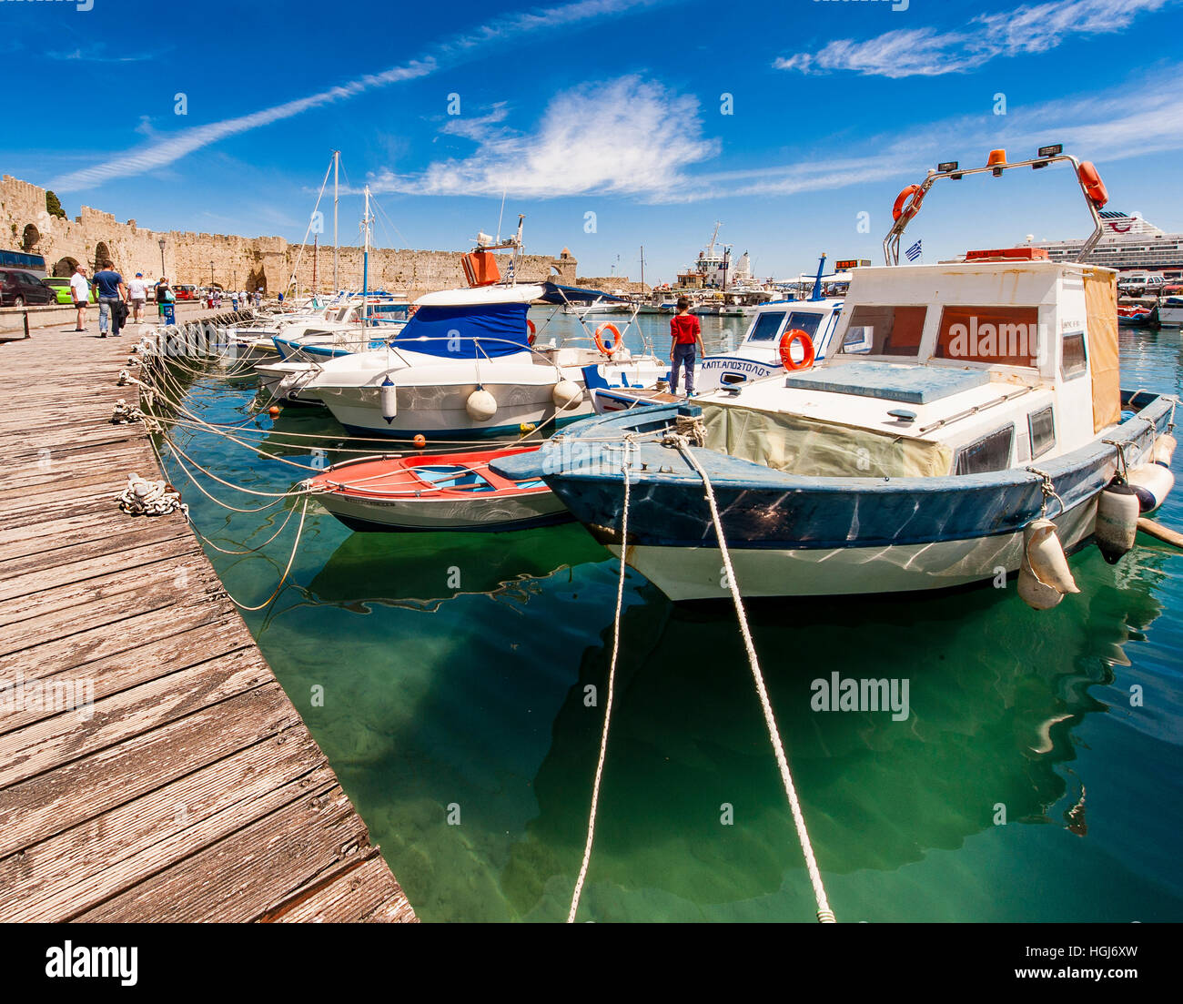 moored boats in rhodes town harbour with ancient wall sweeping from the ...