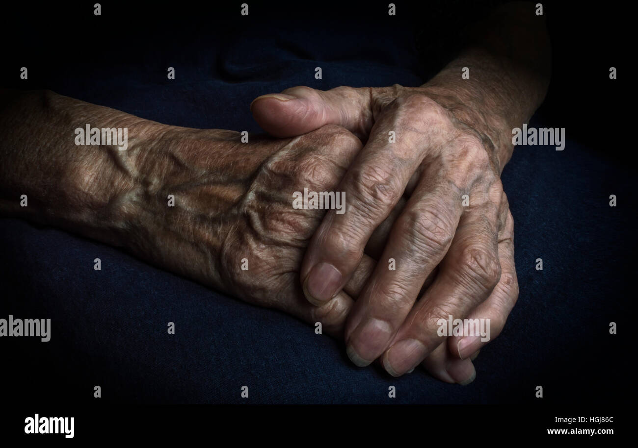 Hands of an old woman with wrinkled and wrinkles on dark background ...