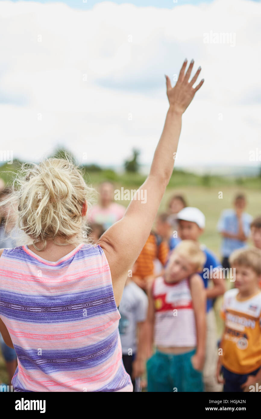 Young woman speaker in front of children crowd. Kids summer camp Stock ...