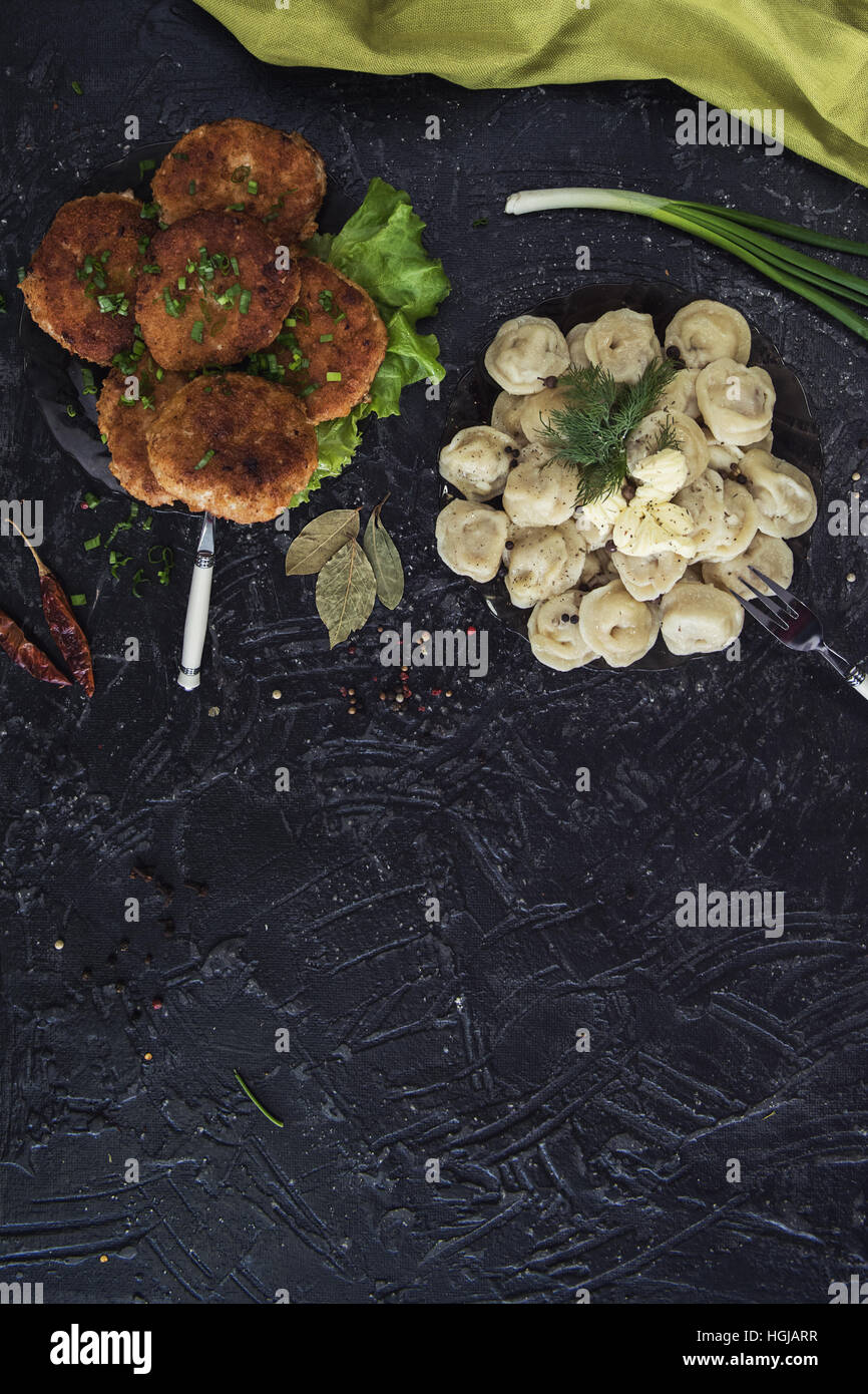 Fried cutlets and russian pelmeni on black background Stock Photo - Alamy