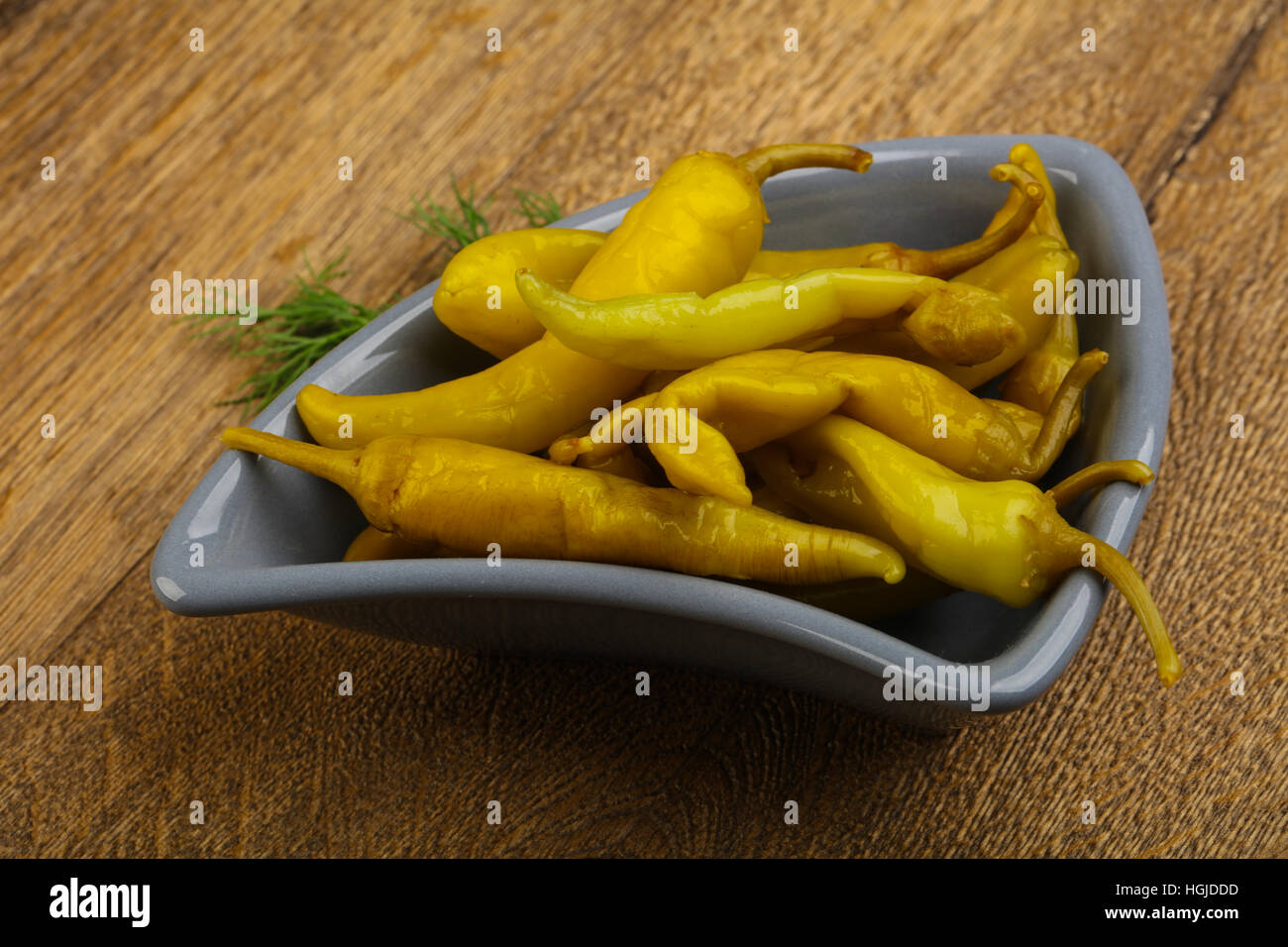 Pickled green pepperoni pepper in the bowl on wood background Stock ...