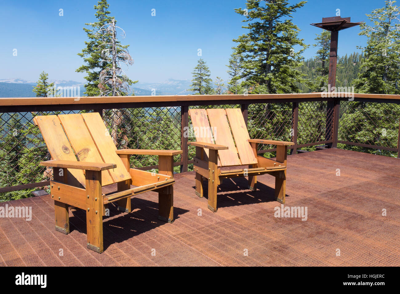 Two wood chairs on outdoor sunny deck with mountains in the background ...
