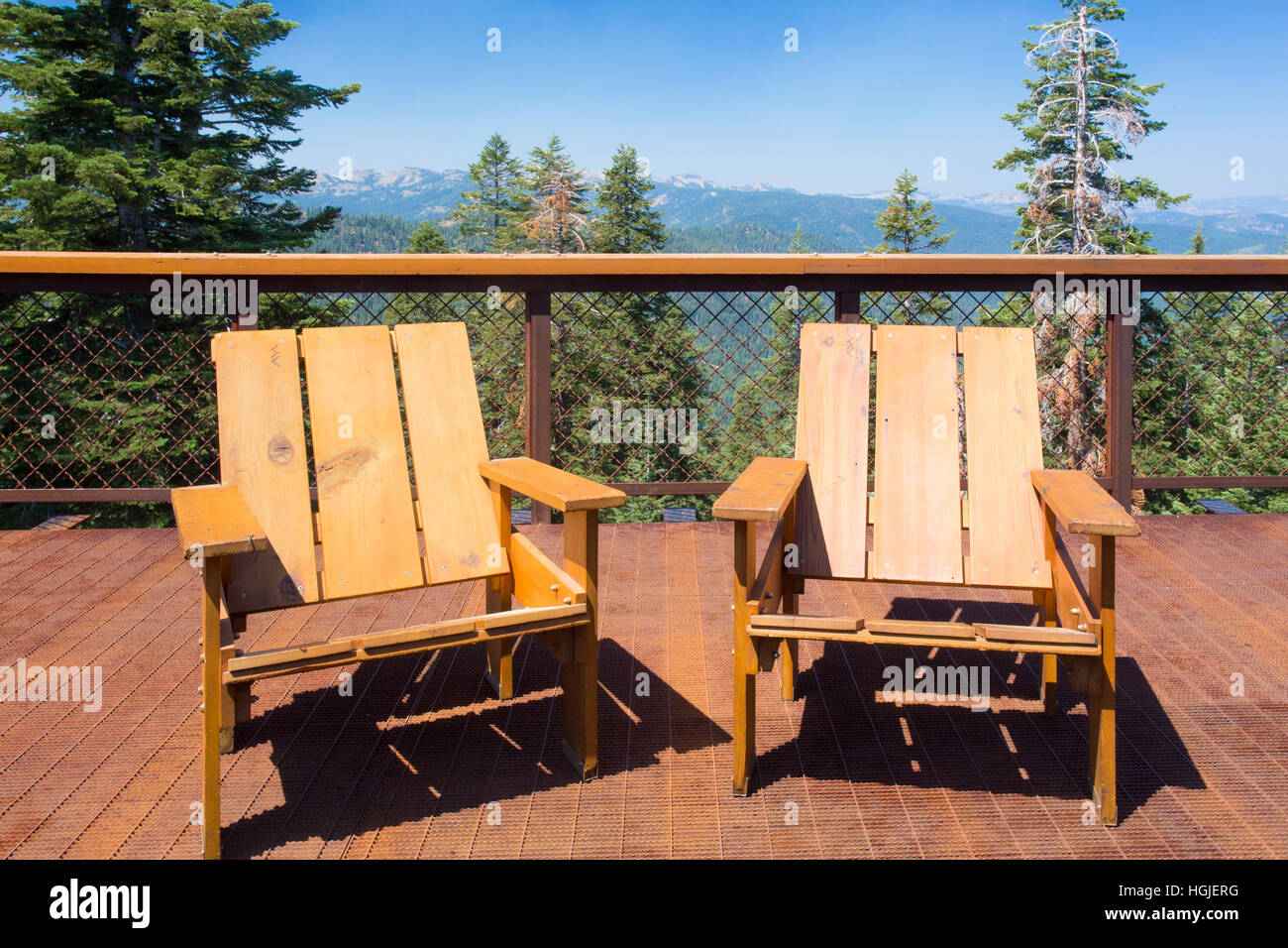 Two wood chairs on outdoor sunny deck with mountains in the background ...